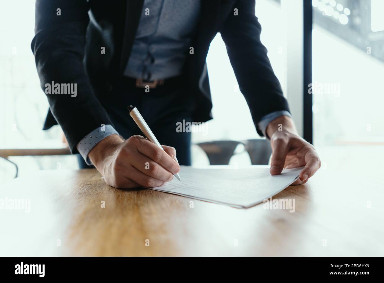 Close up hands signing documents in a modern office with window in ...