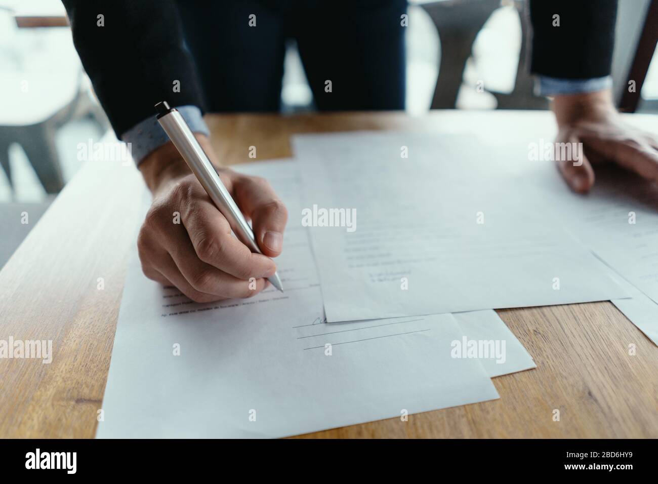 Close up hands signing documents in a modern office with window in ...