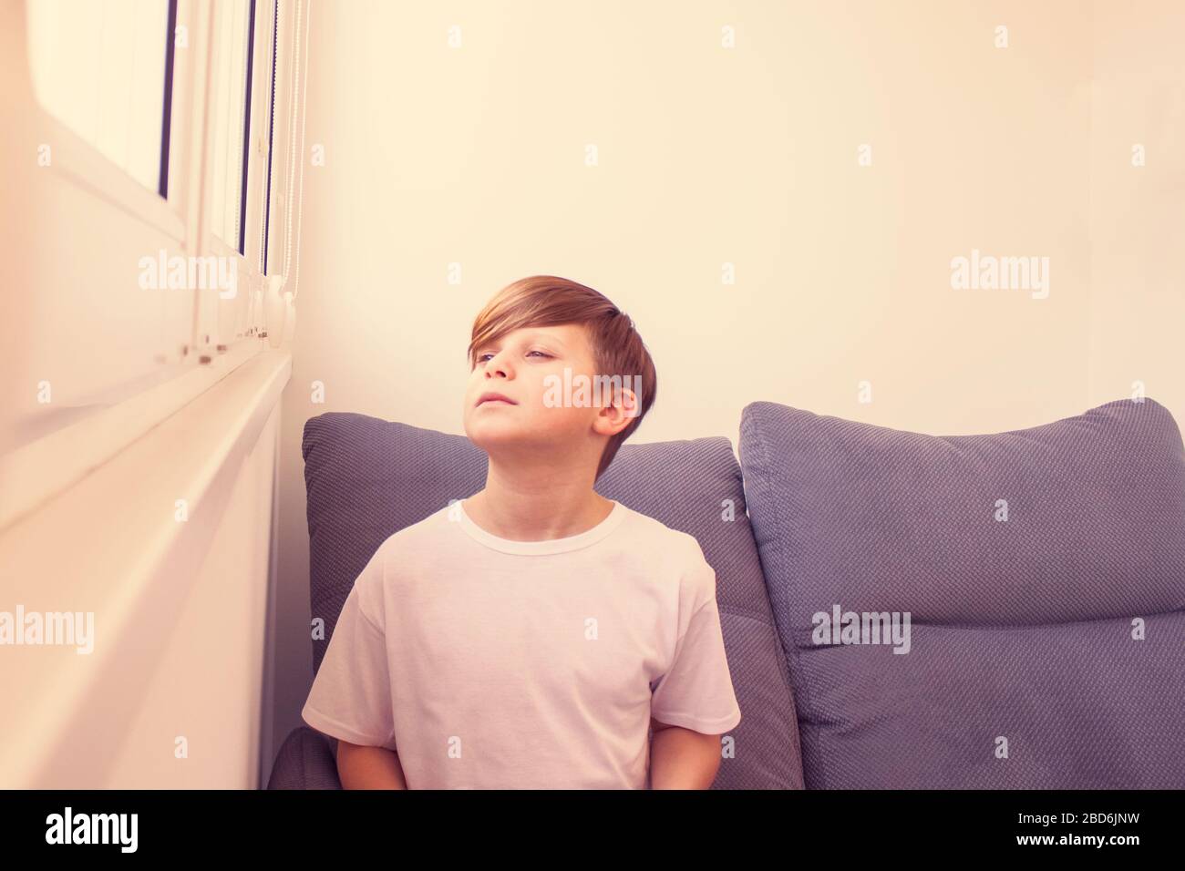 Child boy sitting near window and looking outside Stock Photo - Alamy
