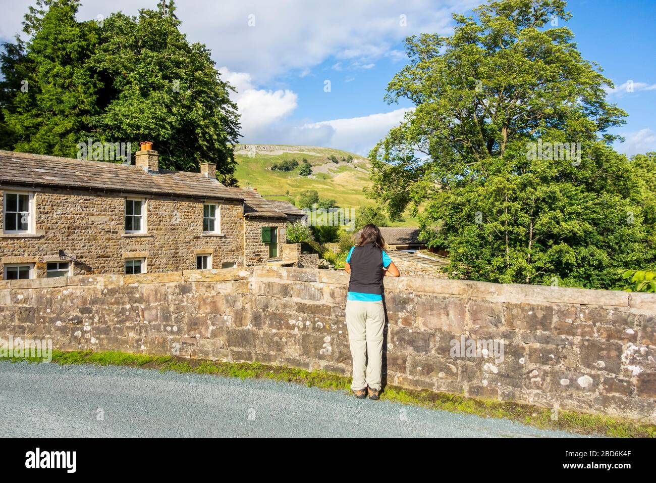 Female walker, hiker on bridge over the river Swale in Swaledale ...