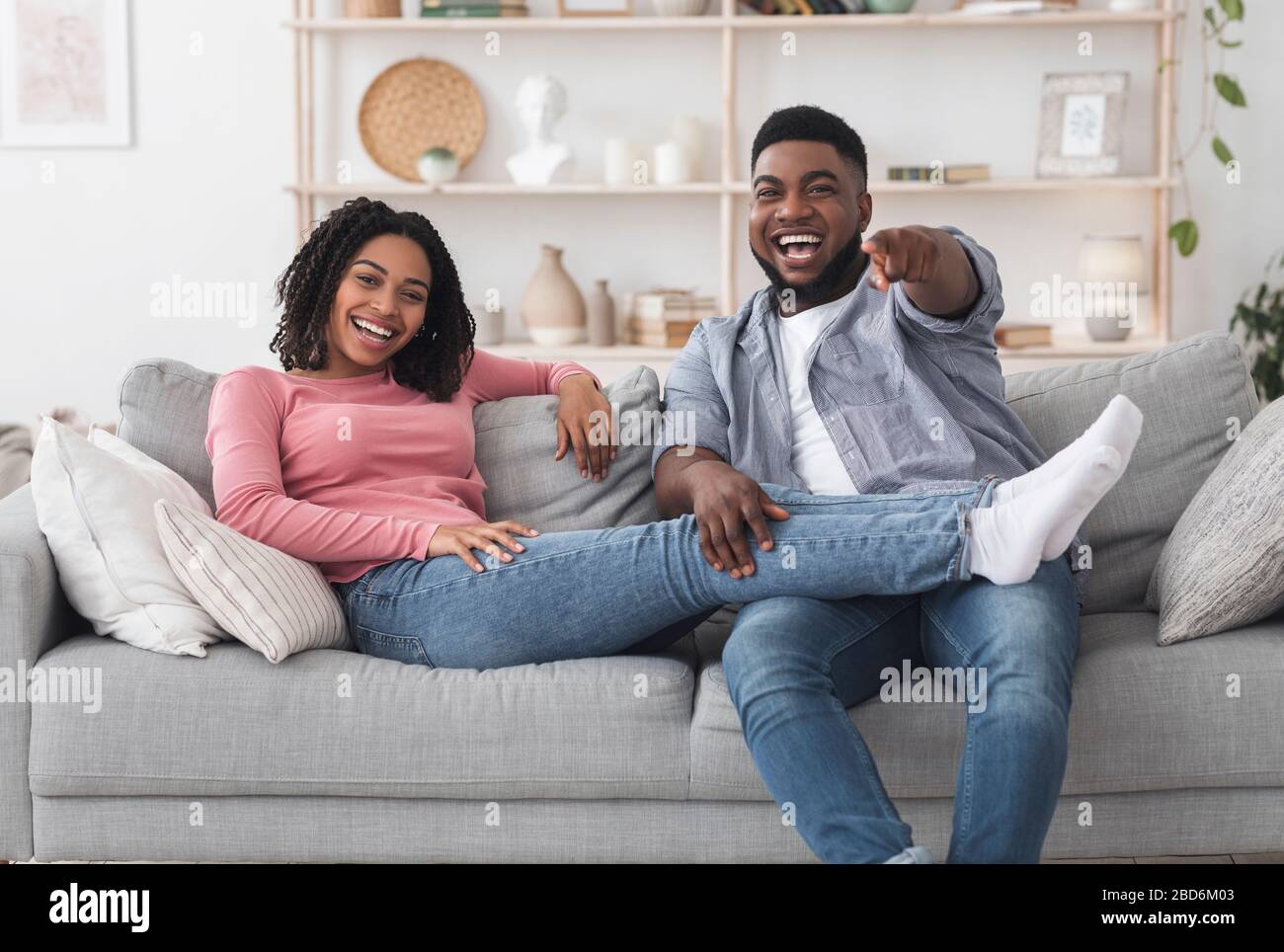 Cheerful black couple watching comedy movie on tv and laughing Stock ...