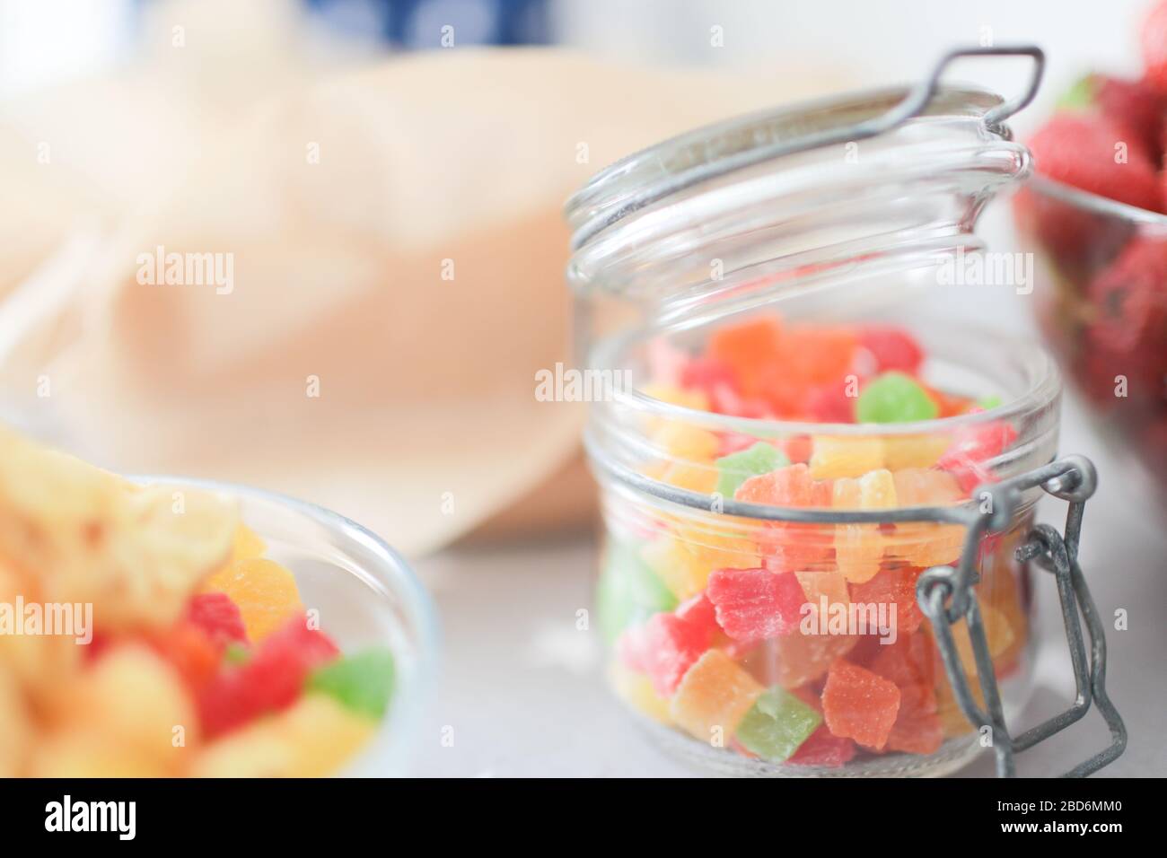Multicolored candied fruits in a transparent stylish jar on the table ...