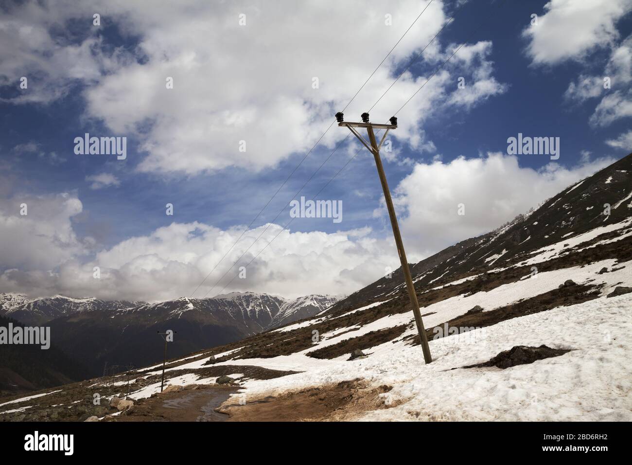 Dirty road with mud and snow and old wooden power poles. High snowy ...