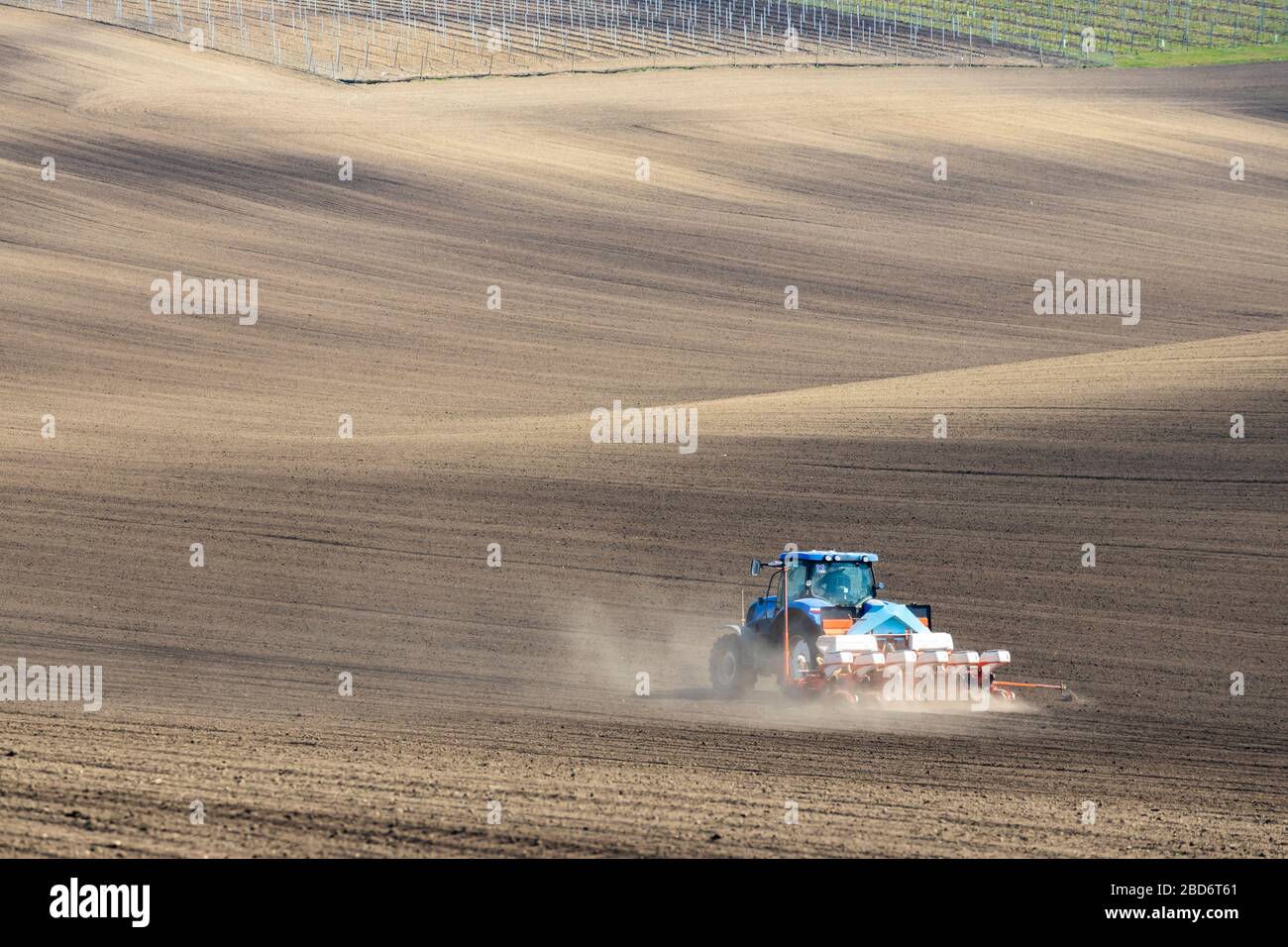 Tractor with seed drill in early spring landscape Stock Photo - Alamy