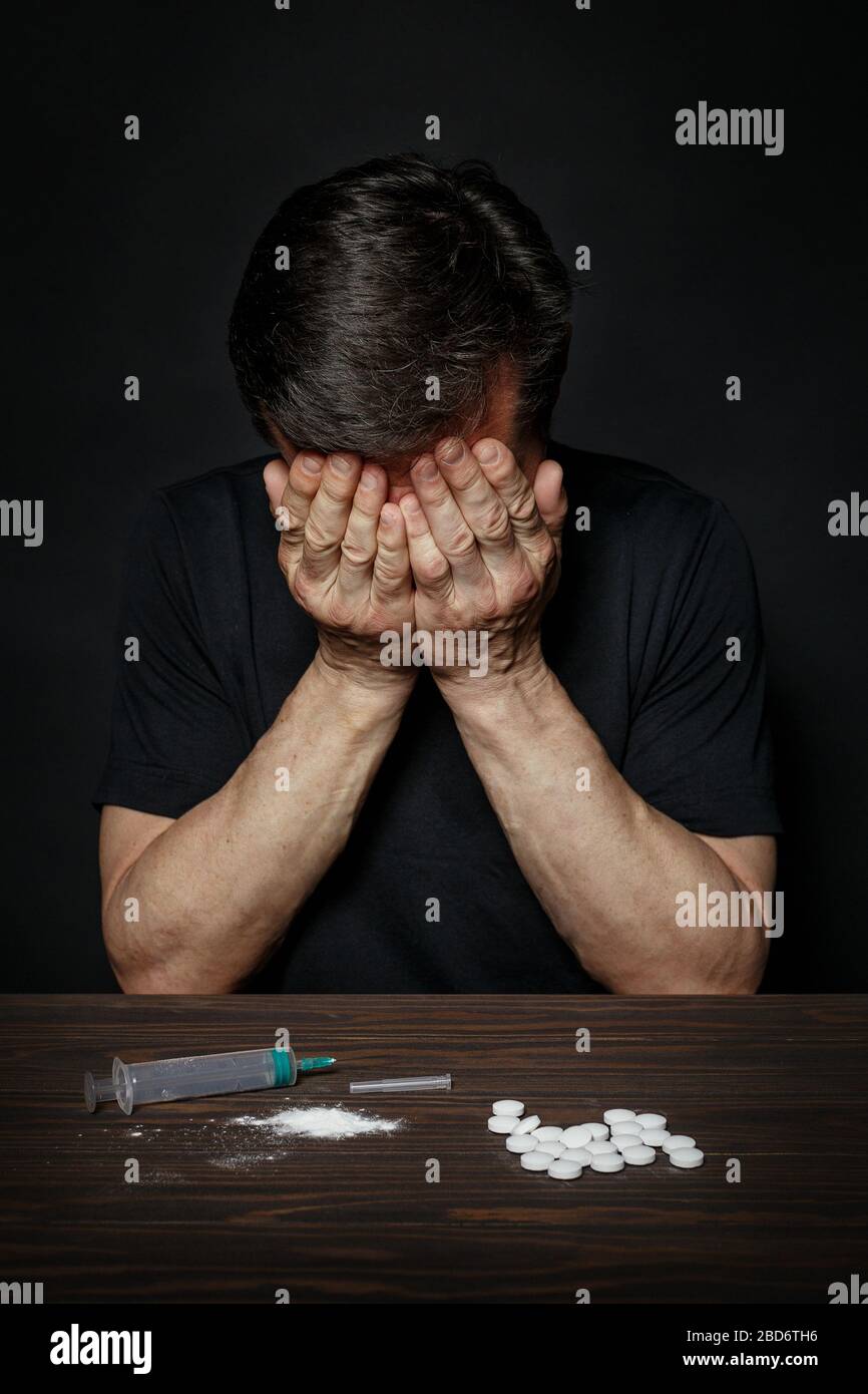 Man in despair from drug addiction is sitting at a table Stock Photo ...