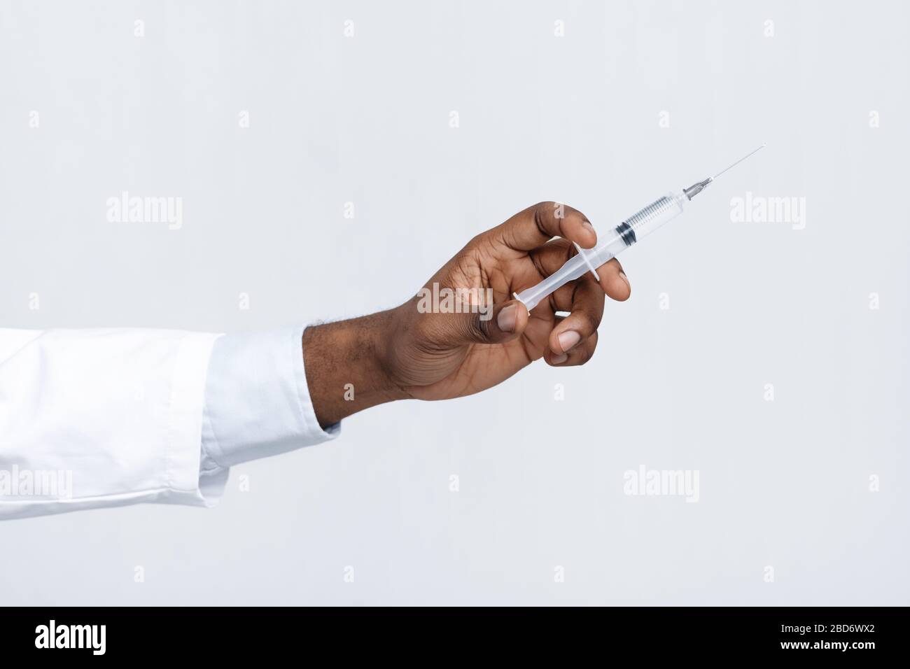 Cropped of black male doctor holding an injection Stock Photo - Alamy
