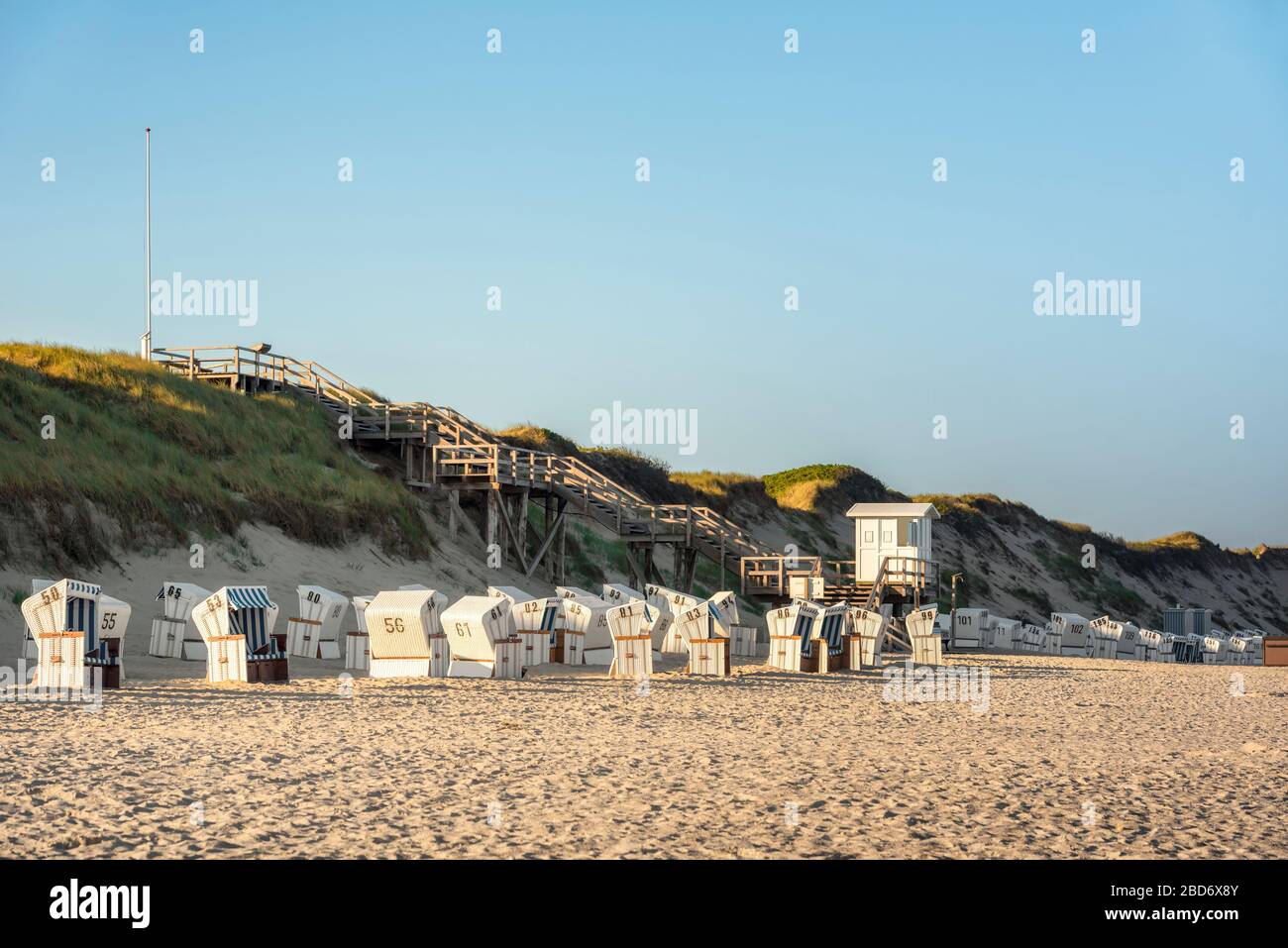 German beach resort with wicker chairs, dunes covered in tall grass in ...