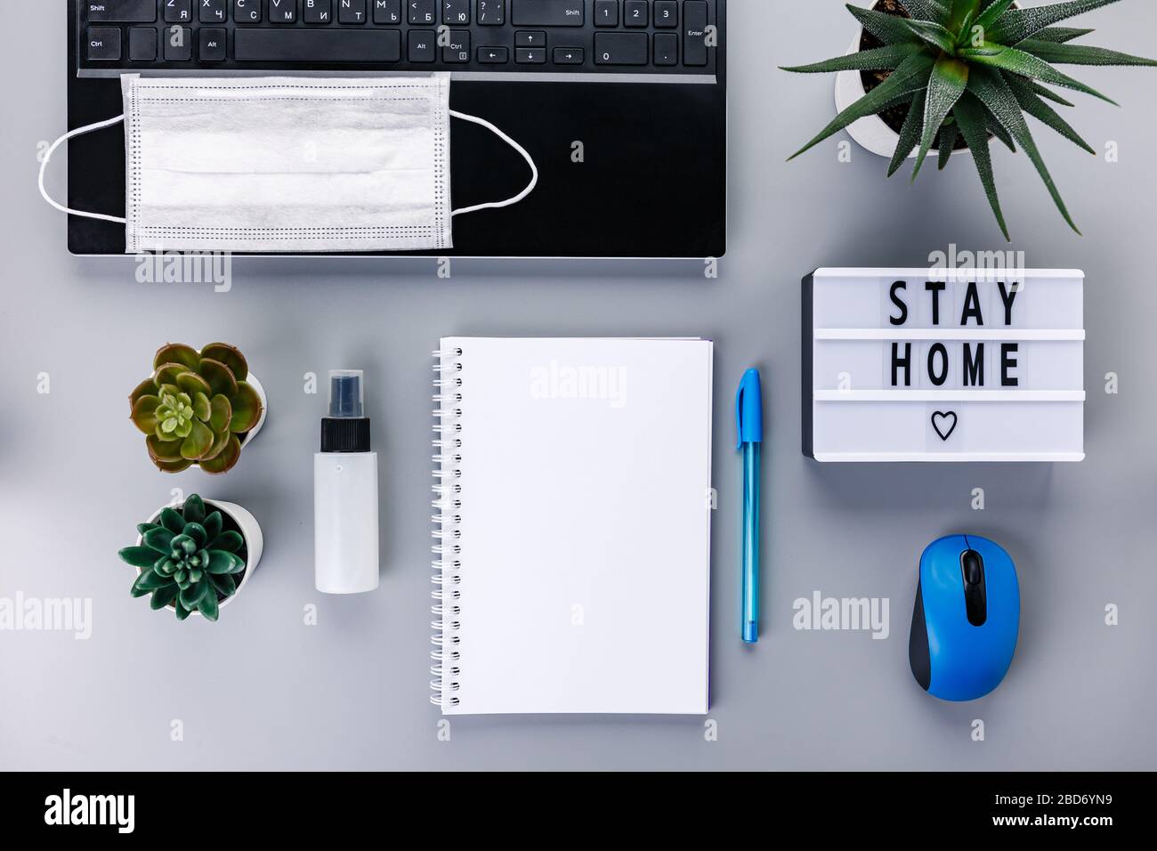 Light box with text STAY HOME, laptop, notepad, medicine mask and ...