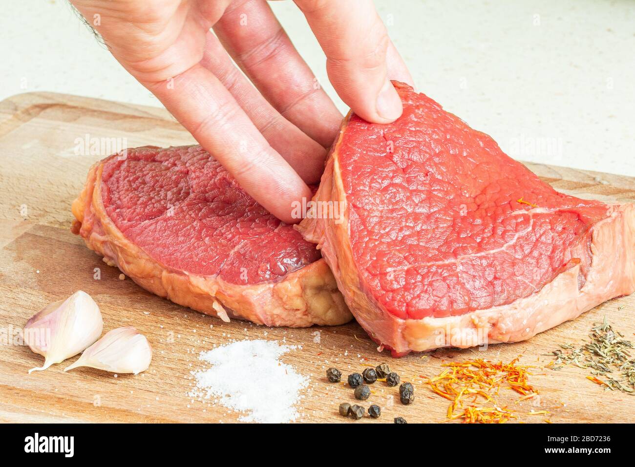 Close up mans hand touches meat on a wooden table. Concept of healthy ...