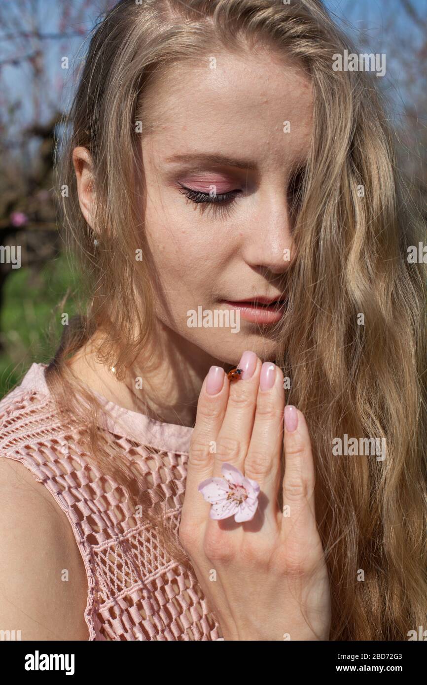 Beautiful blonde woman in pink dress and ladybug insect Stock Photo - Alamy