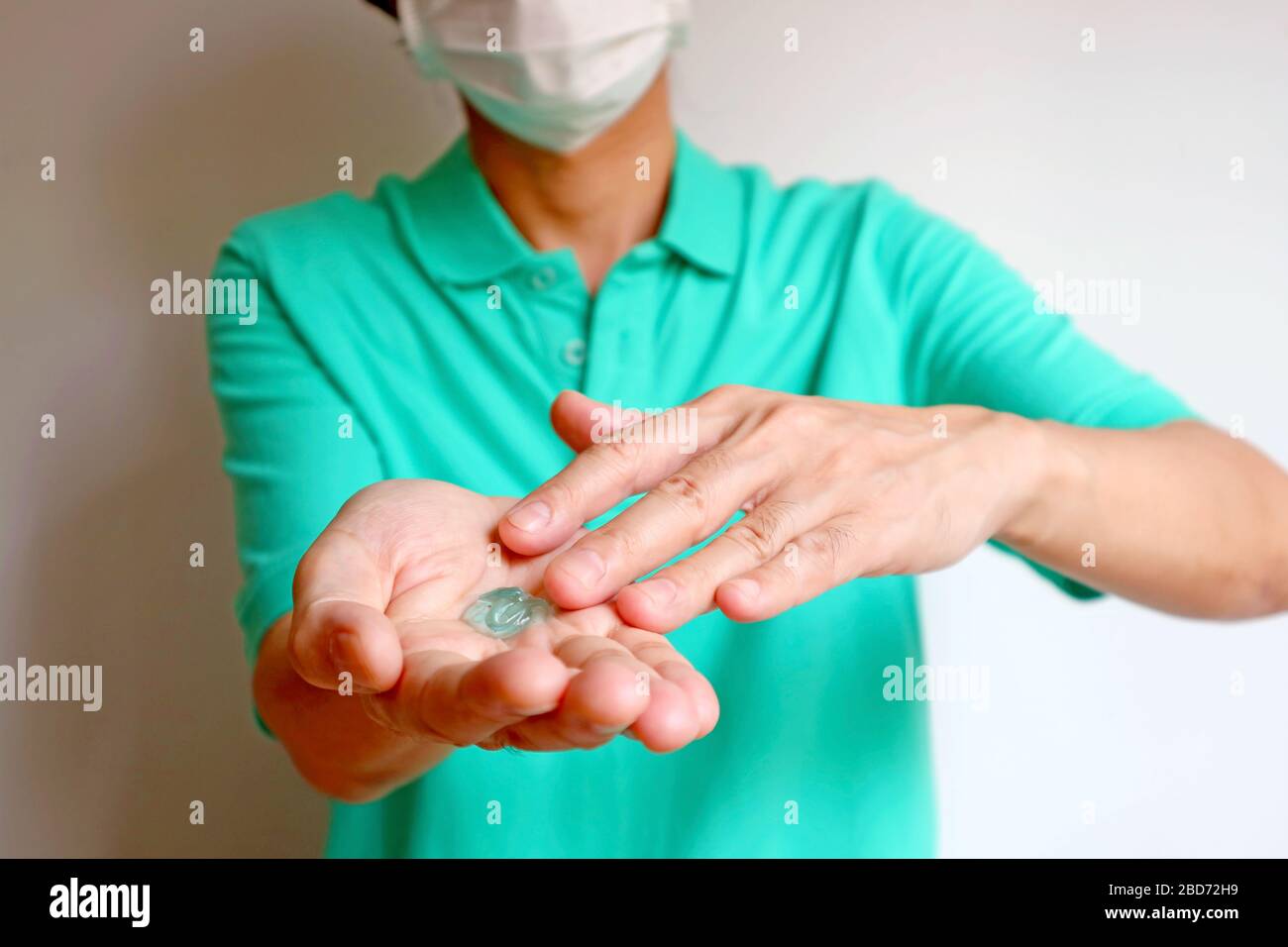 Man with Face Mask Using Alcohol Cleansing Gel Rubbing His Hands to ...
