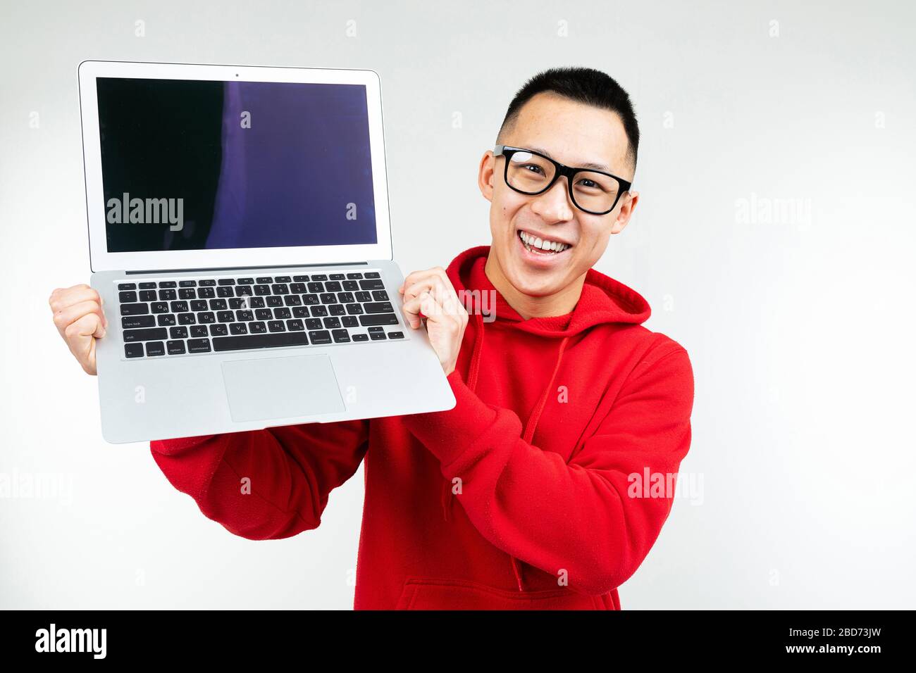 Asian man shows laptop screen with mockup on white studio background ...