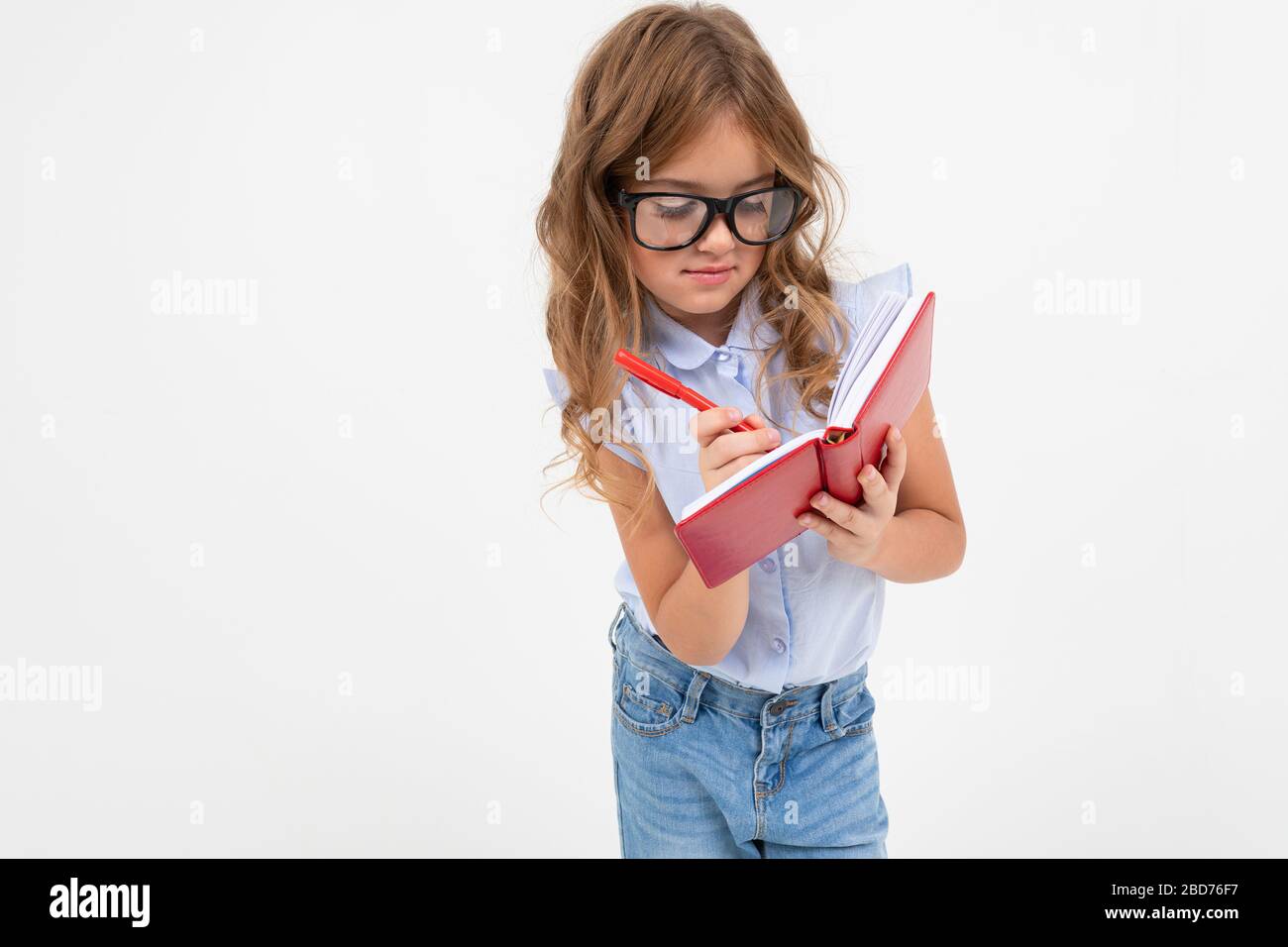 smart girl with glasses writes in a notebook on a white background with ...