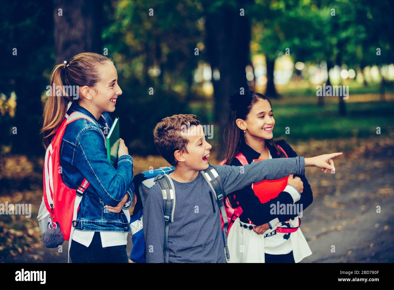 Back to school. Close up three happy friends with backpacks laughing ...