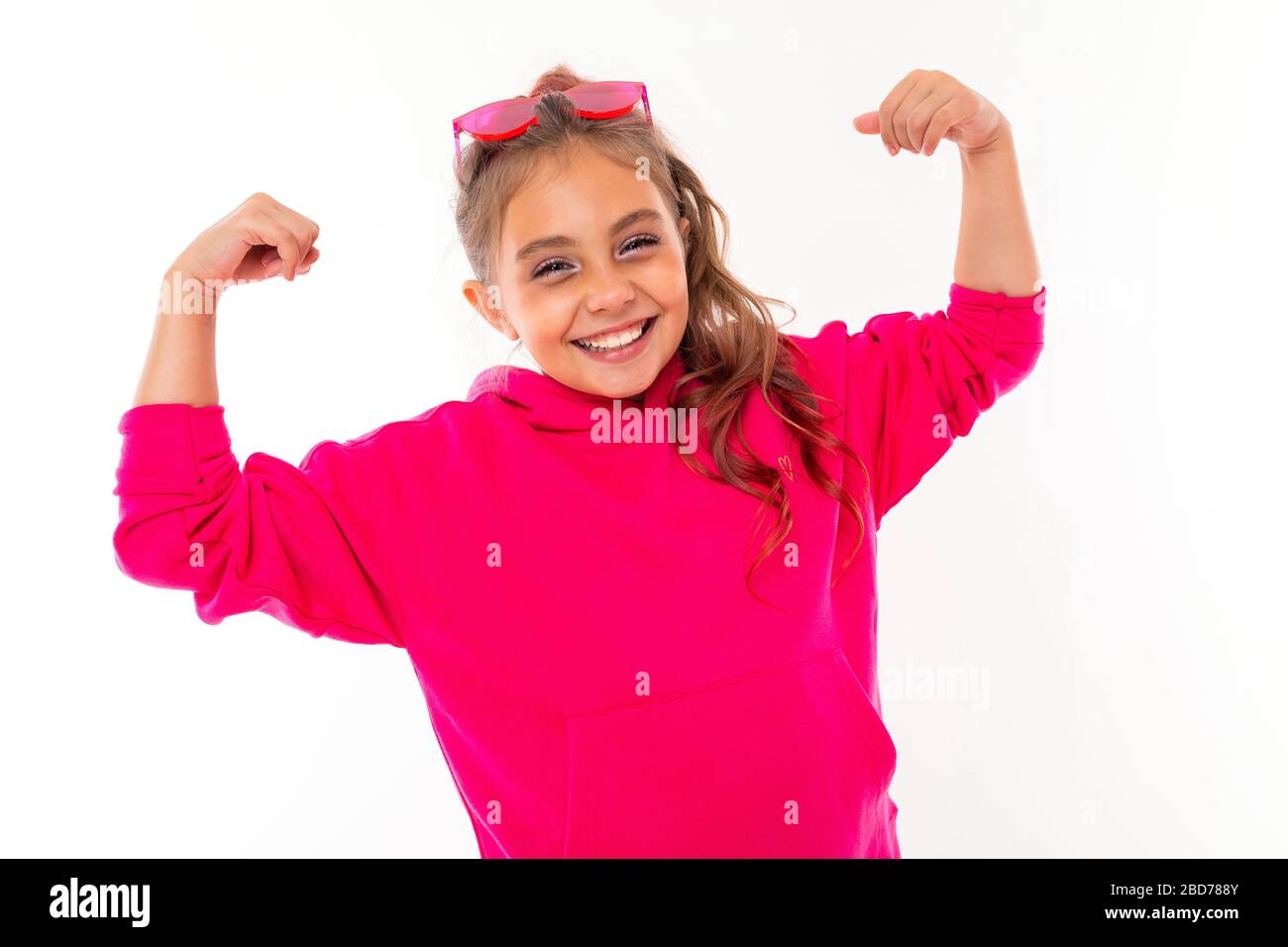 girl in a pink sweater shows strong muscles on a white background with ...