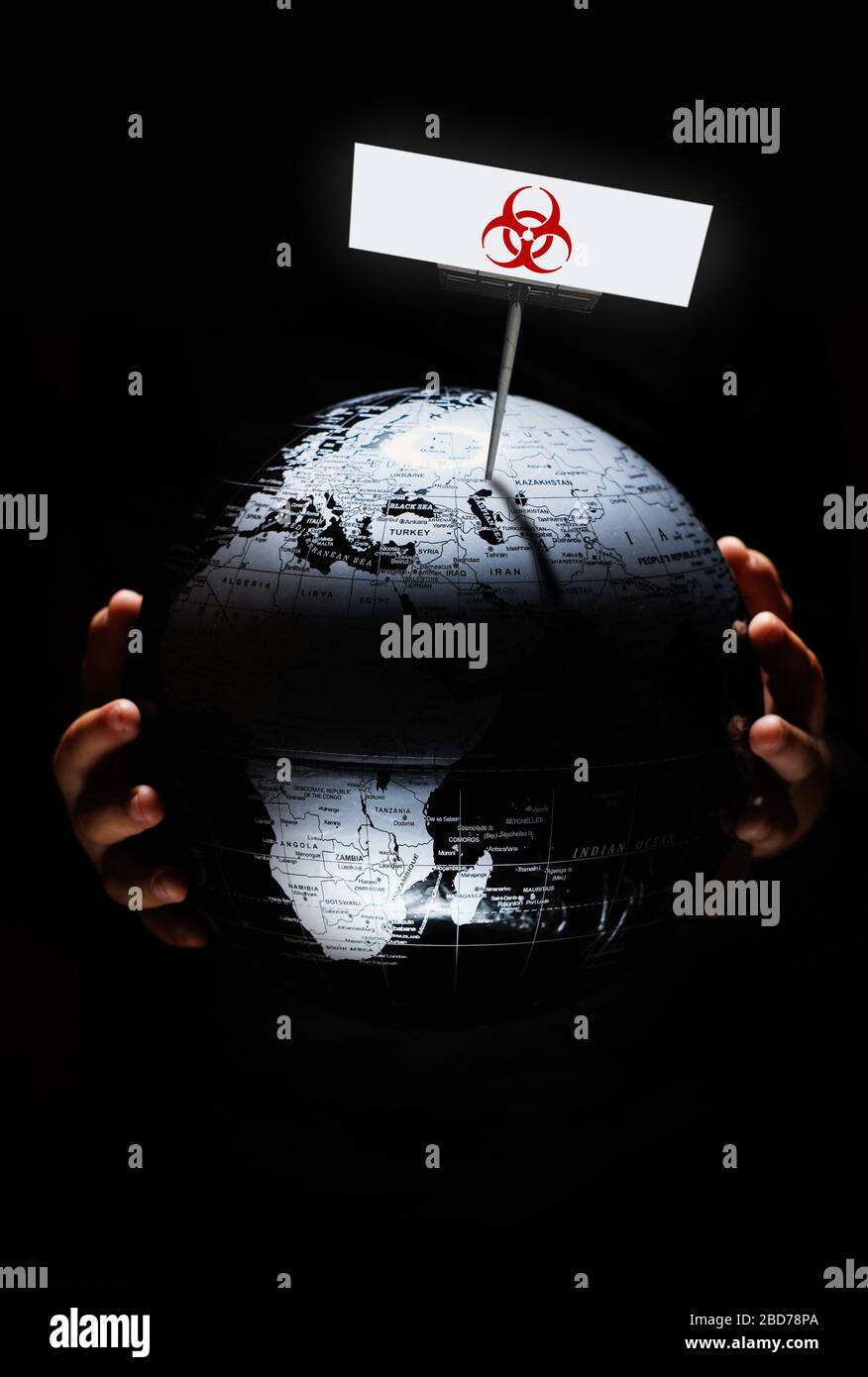Close up kid hands hold globe with red biohazard sign on it on black ...
