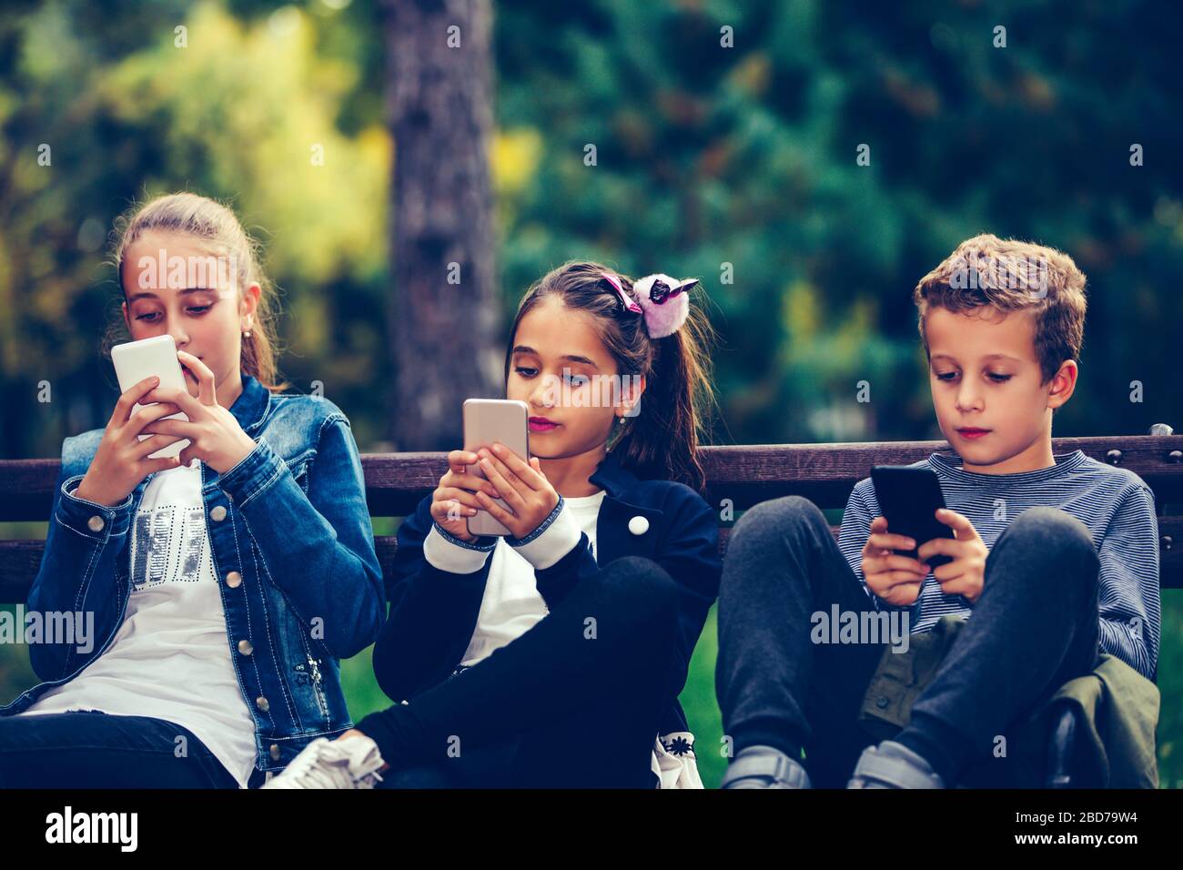 Group of friends playing video games on smart phone after school while ...