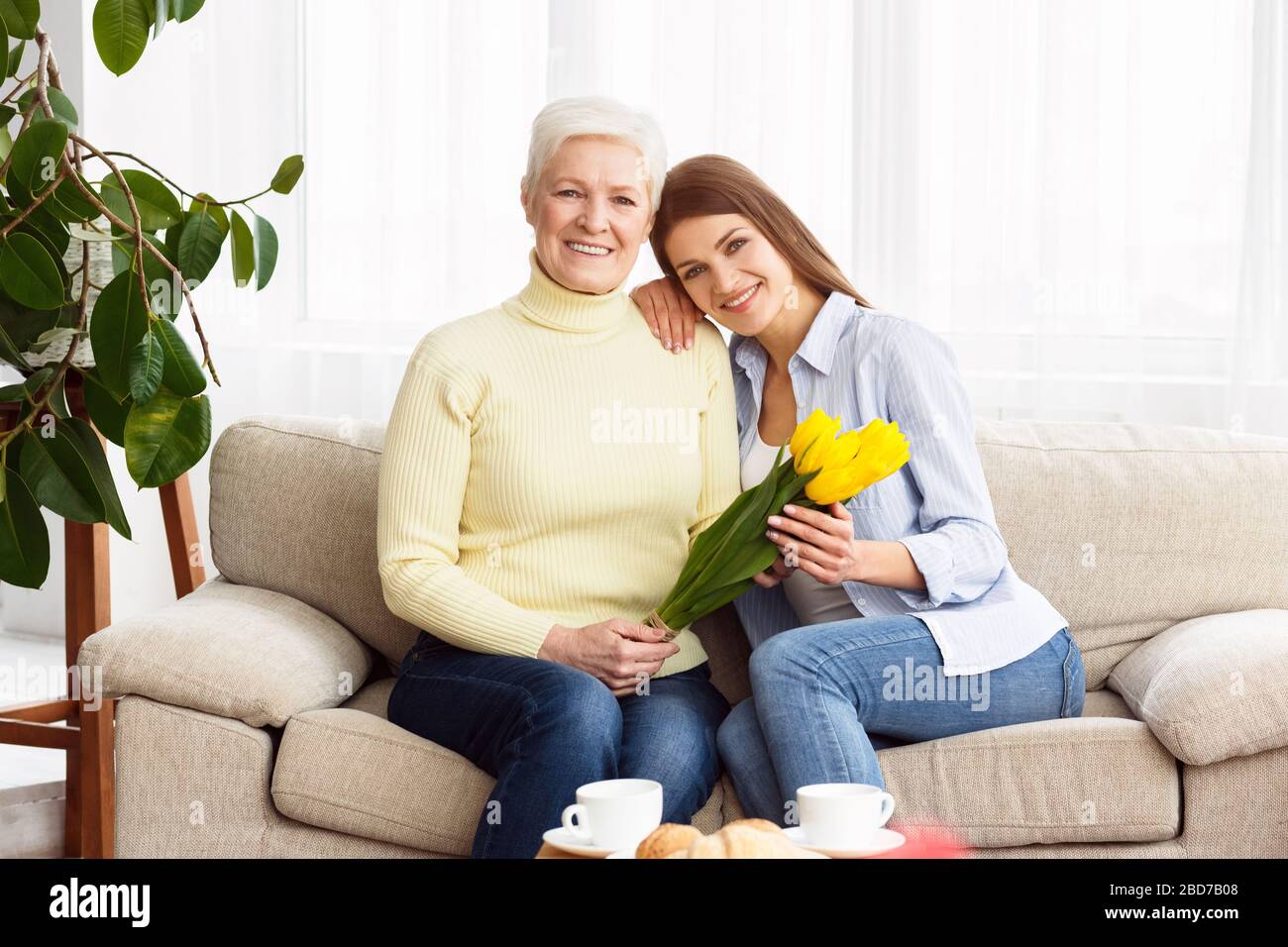 Family values. Mother and daughter with yellow tulips Stock Photo - Alamy