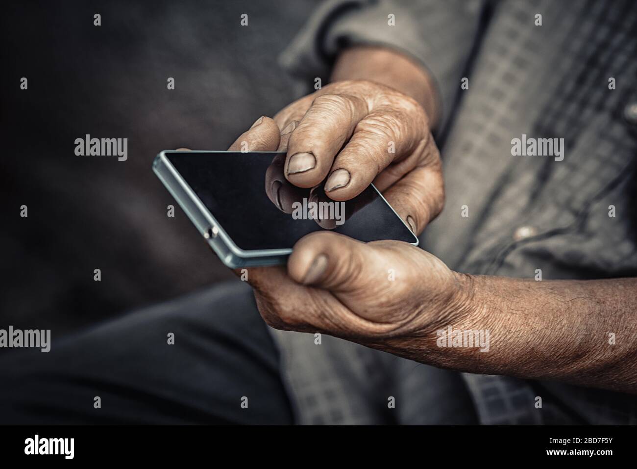 Elderly & technology. Senior old man using phone isolated dark black ...