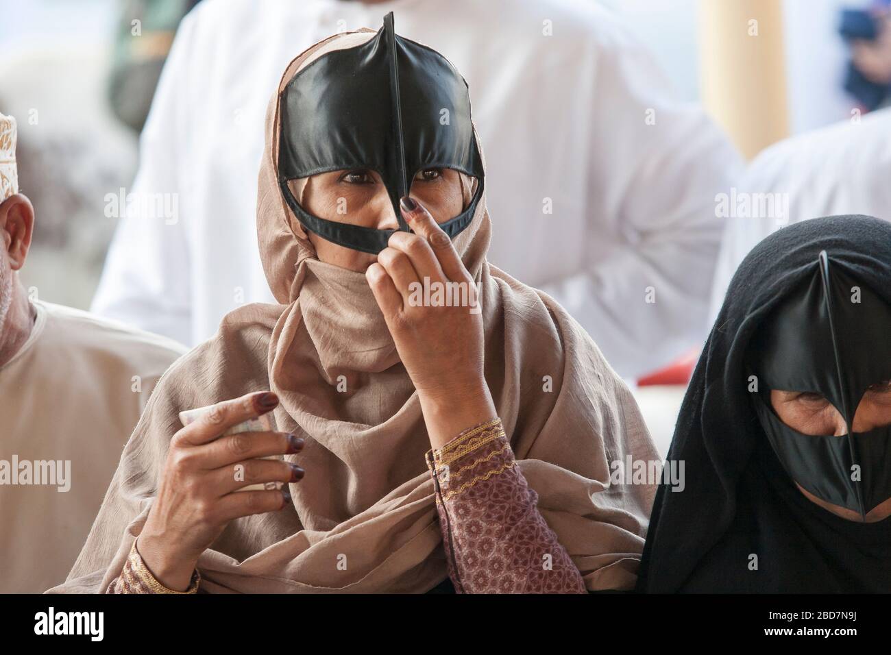 Omani women wearing a Batoola haggle for livestock at the friday market ...
