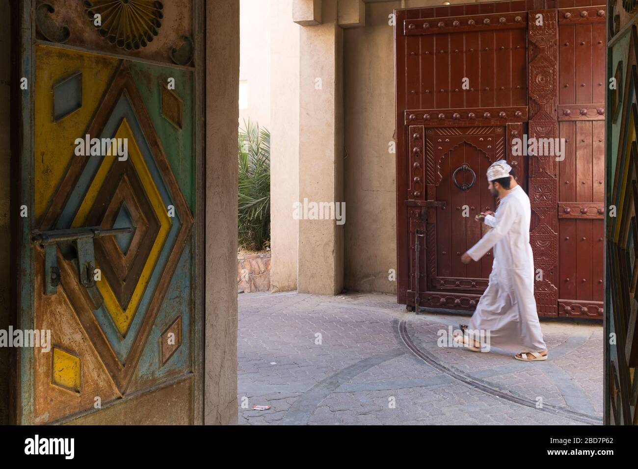 Omani men in dishdasha walk past ornate and decorative traditional ...