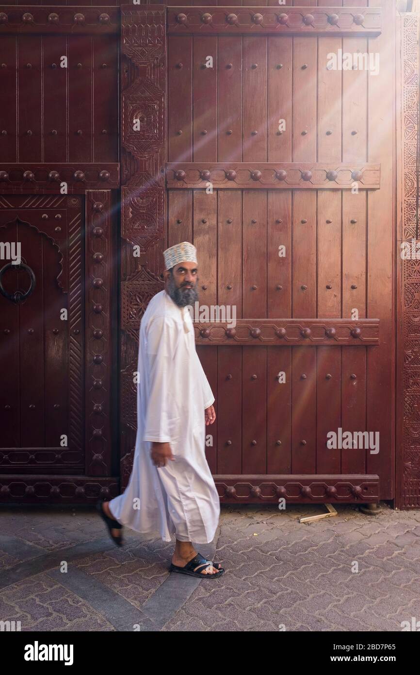 Omani men in dishdasha walk past ornate and decorative traditional ...