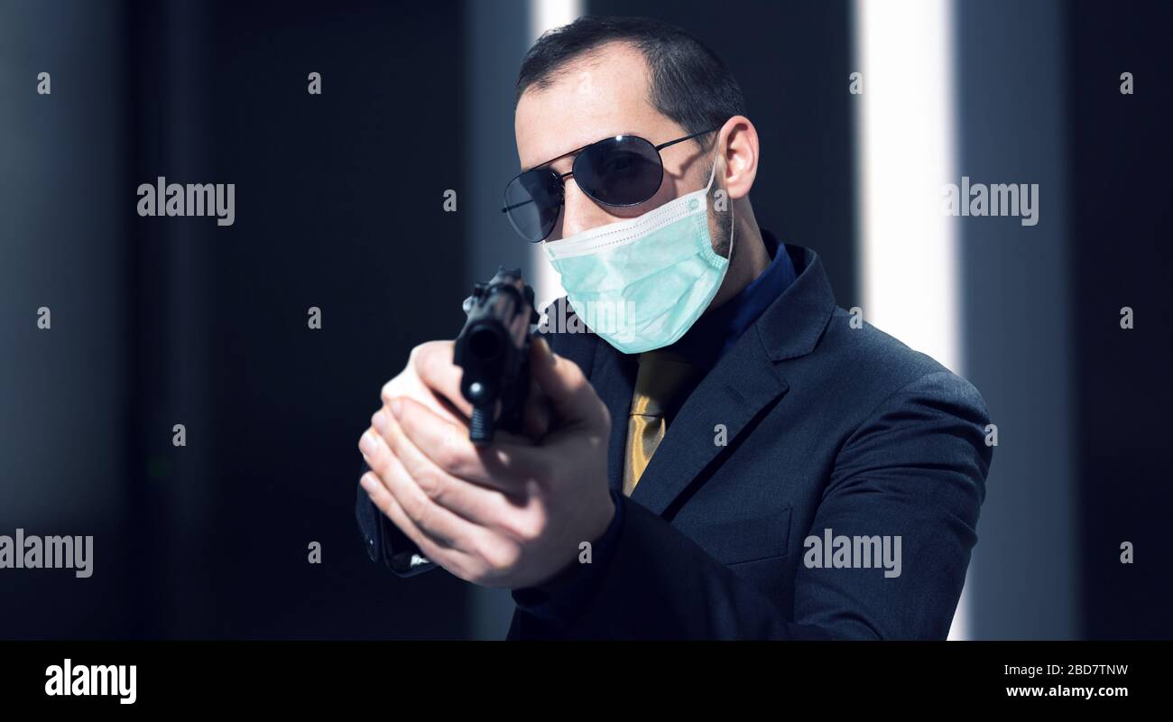 Secret agent holding a gun while wearing a mask, coronavirus and ...