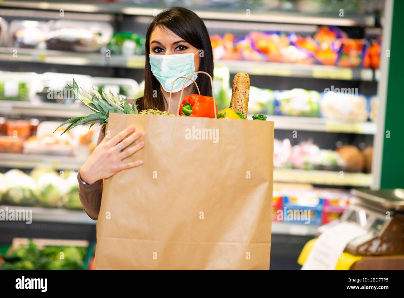 Masked woman holding an healthy food bag in a grocery store Stock Photo ...