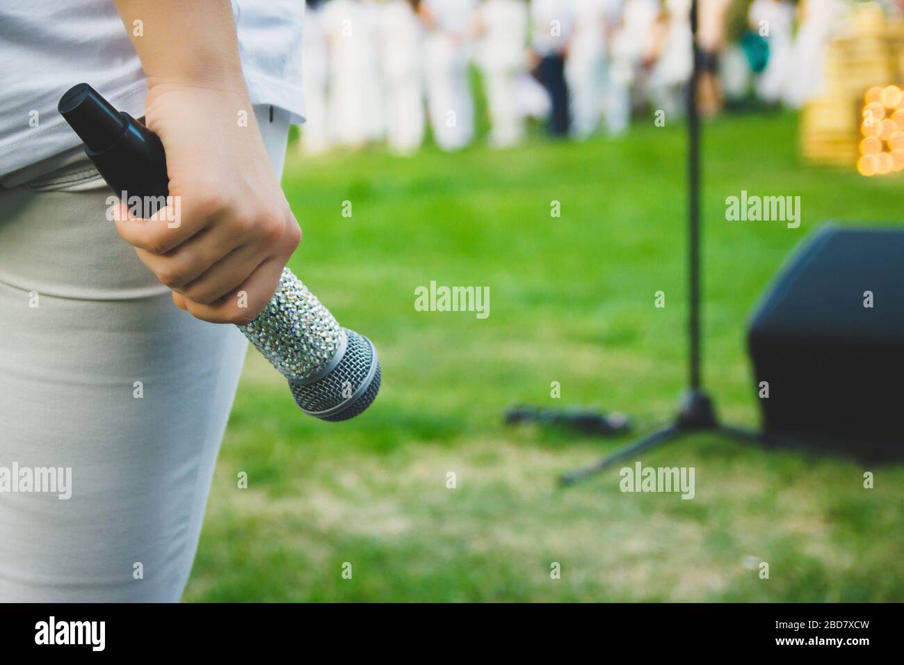 A slender woman in white clothes with a microphone in her hand stands ...