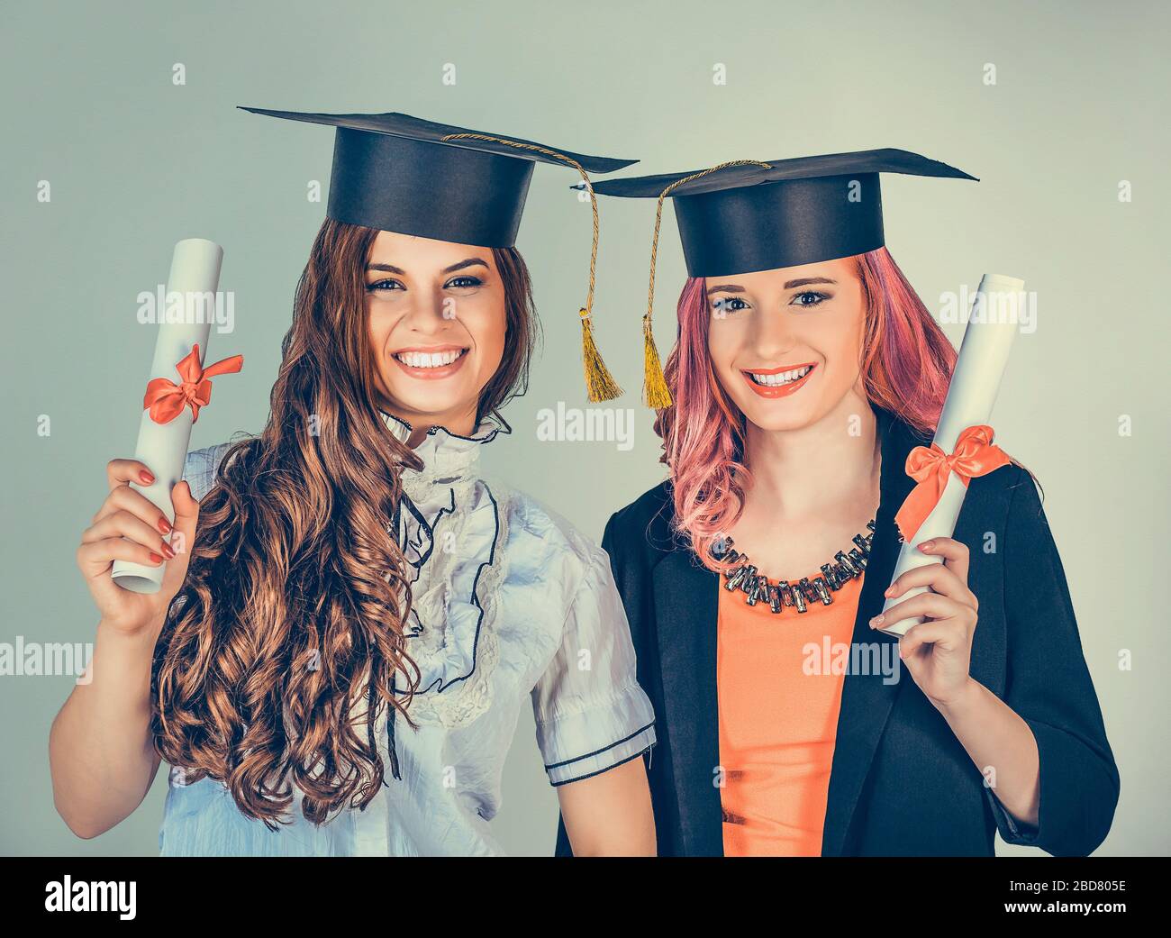 Portrait closeup beautiful happy graduates, two graduated student girls ...