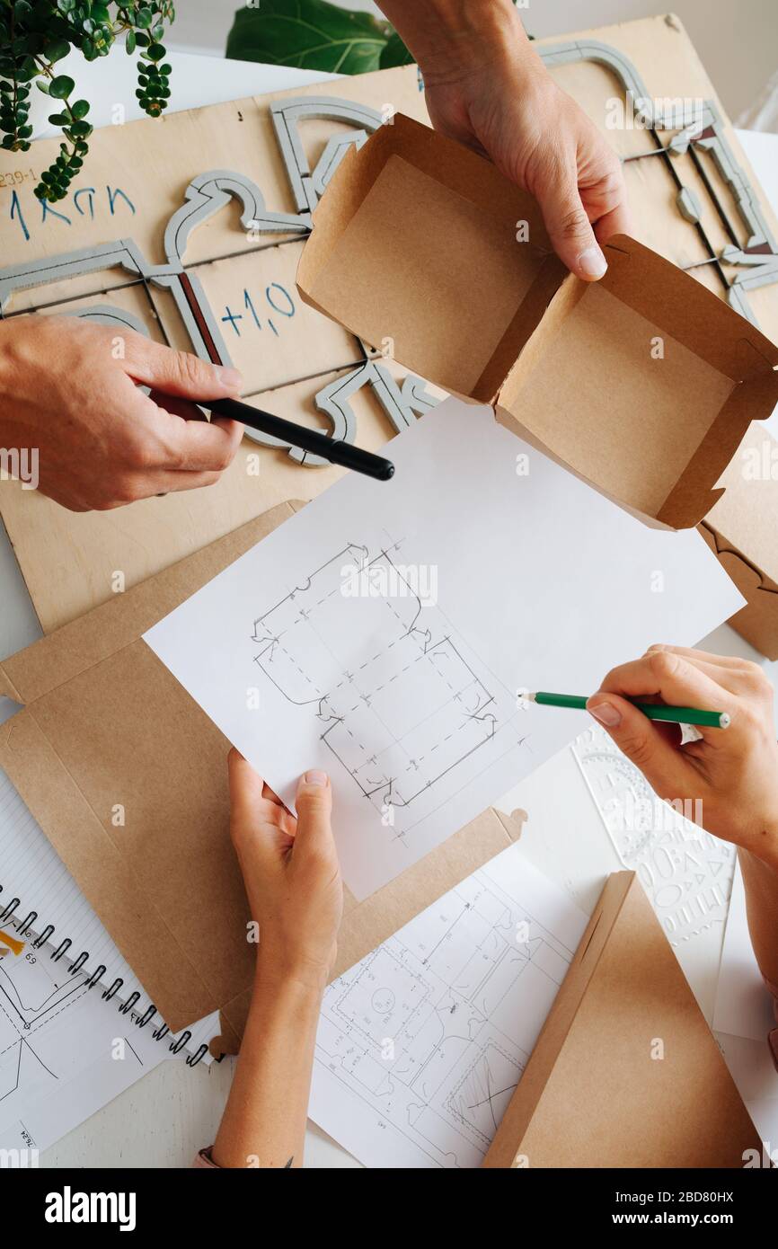 Box makers working behind a table, discussing schematics of a box Stock ...