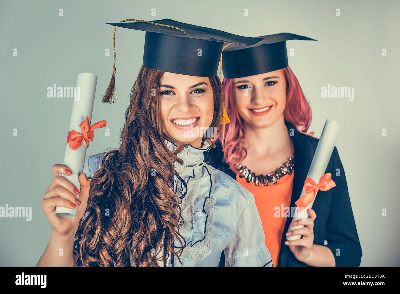 Portrait closeup beautiful happy graduates, two graduated student girls ...