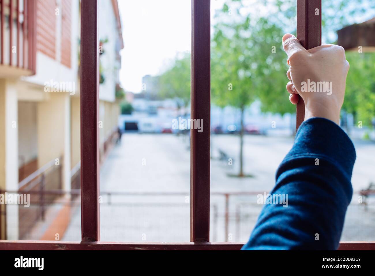 a woman's hand grabbing the bars of a window Stock Photo - Alamy