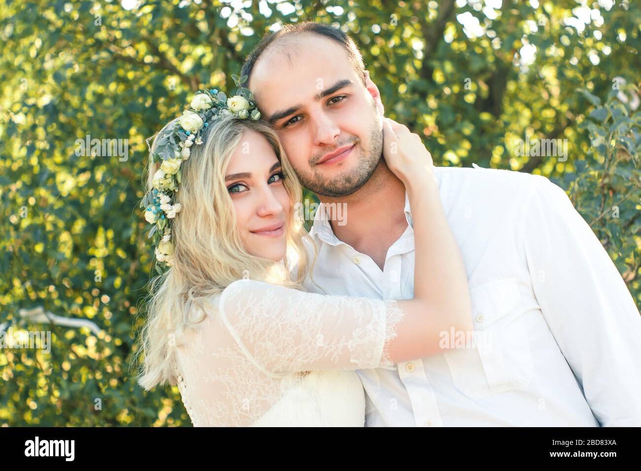 Bride in white dress and wreath and groom portrait in sunny summer day ...