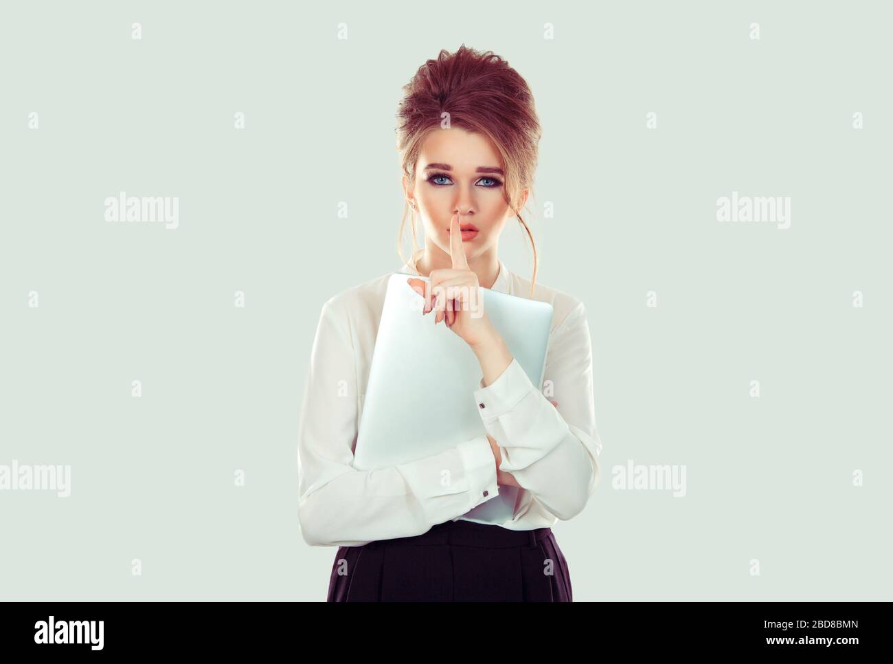 Shh. Woman wide eyed asking for silence or secrecy with finger on lips ...