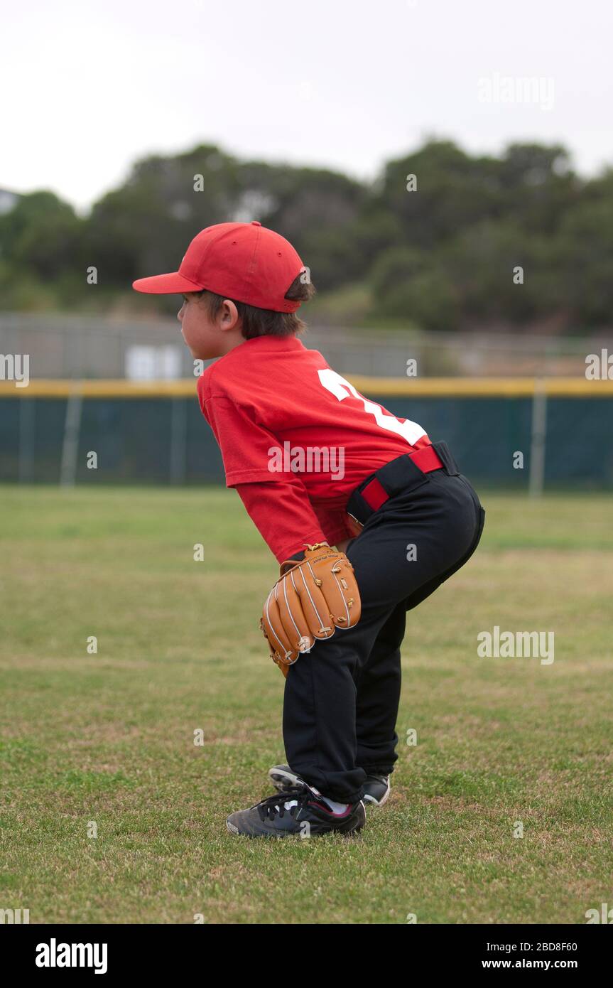 Young boy with his hands and glove on his kees on a baseball field ...