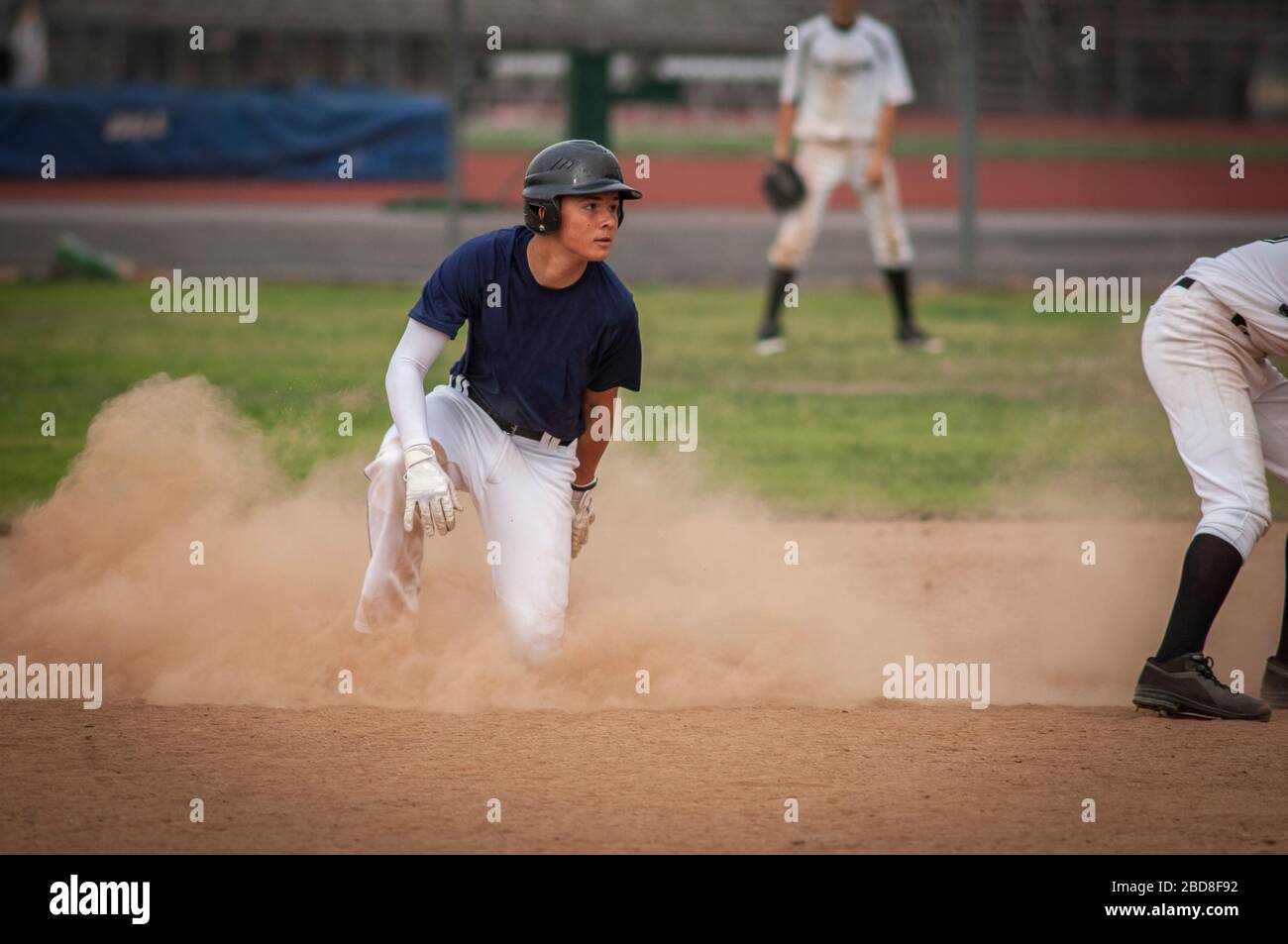 Young baseball player in cloud of dust after sliding into second base ...