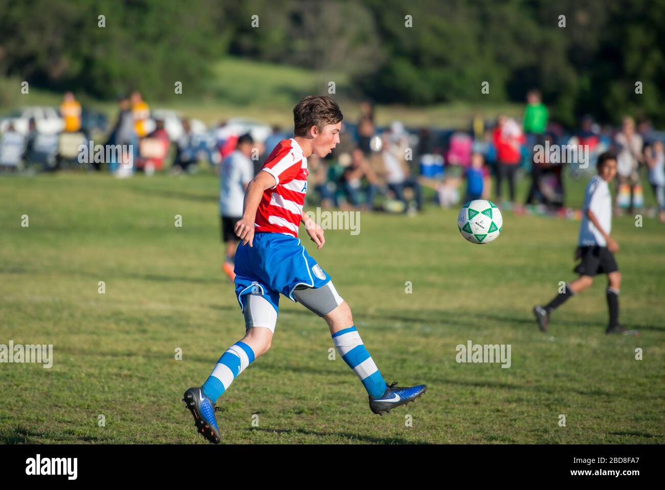 teen soccer player running and kicking the ball Stock Photo - Alamy