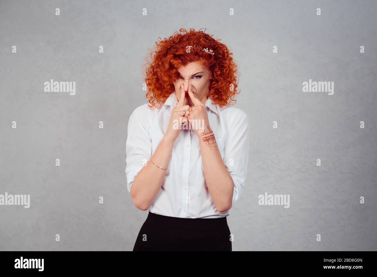 Stinky. Closeup portrait young red head business woman pinches her nose ...