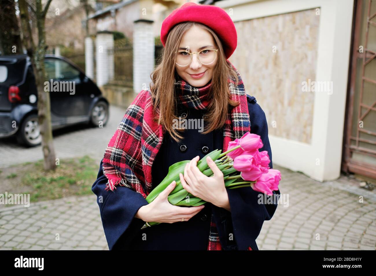 young french millennial girl in beret and coat with tulips in hands ...