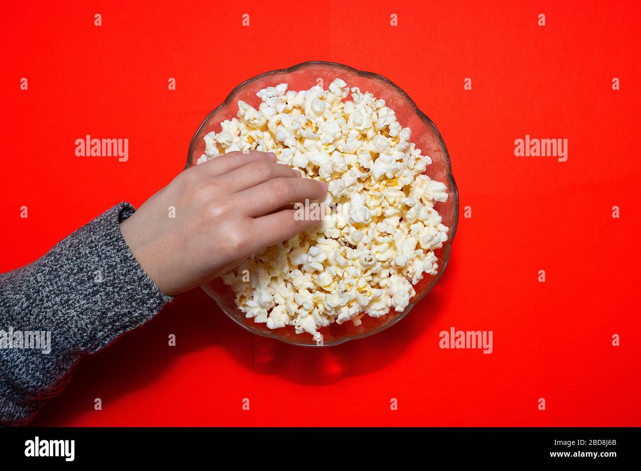 Hand picking up popcorn on a red background. Popcorn concept Stock ...