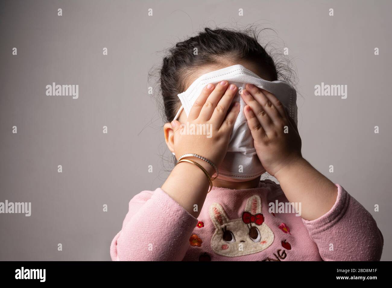 Mischievous little girl playing with wearing mask on her face ...