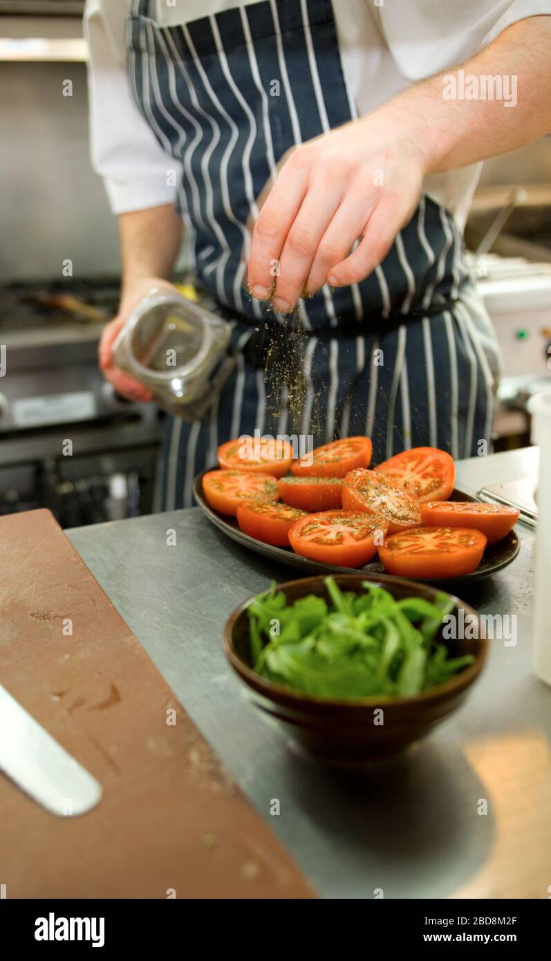 chef sprinkles herbs on tomatoes in restaurant kitchen Stock Photo - Alamy