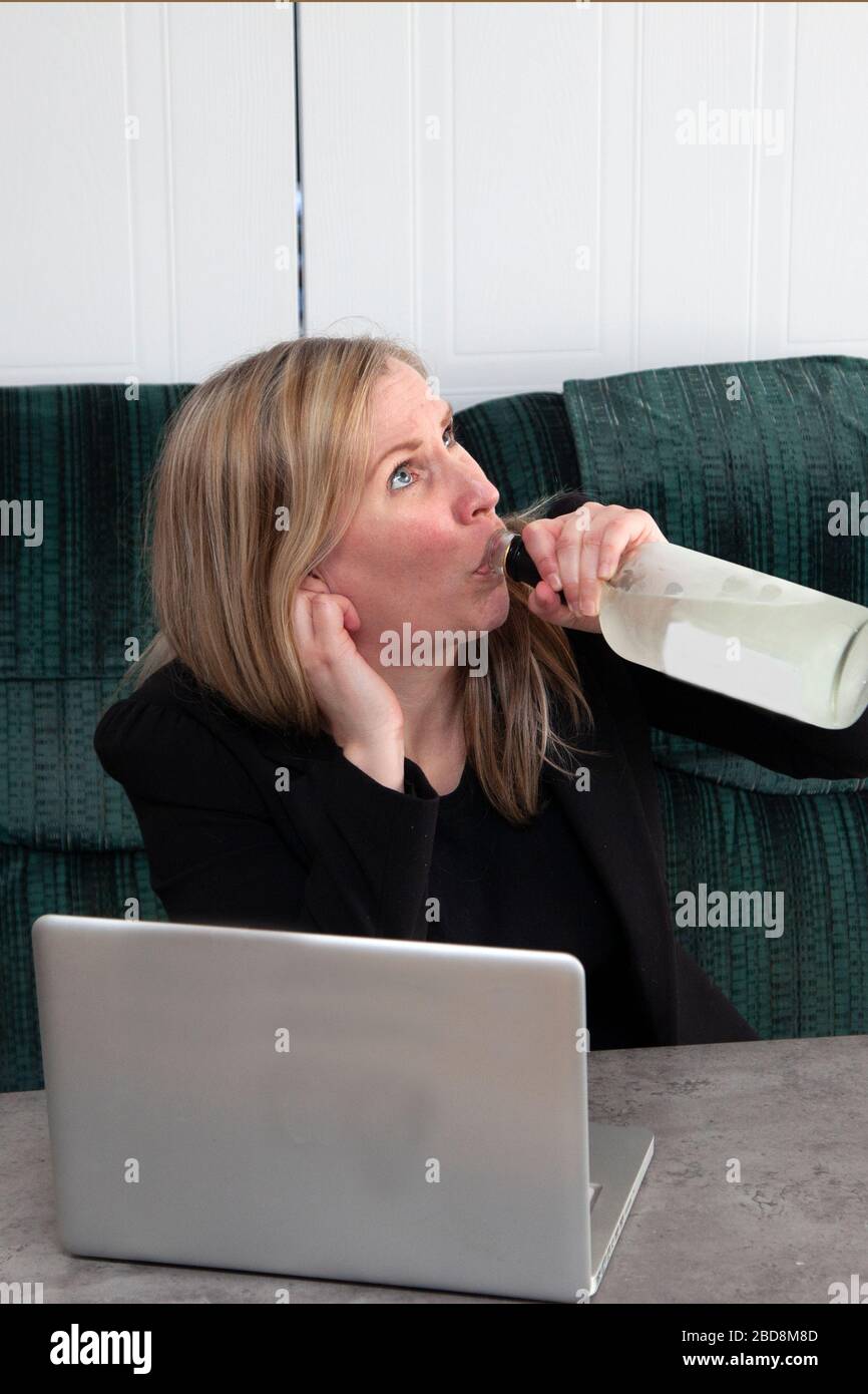 woman on her laptop with a big bottle of booze Stock Photo - Alamy