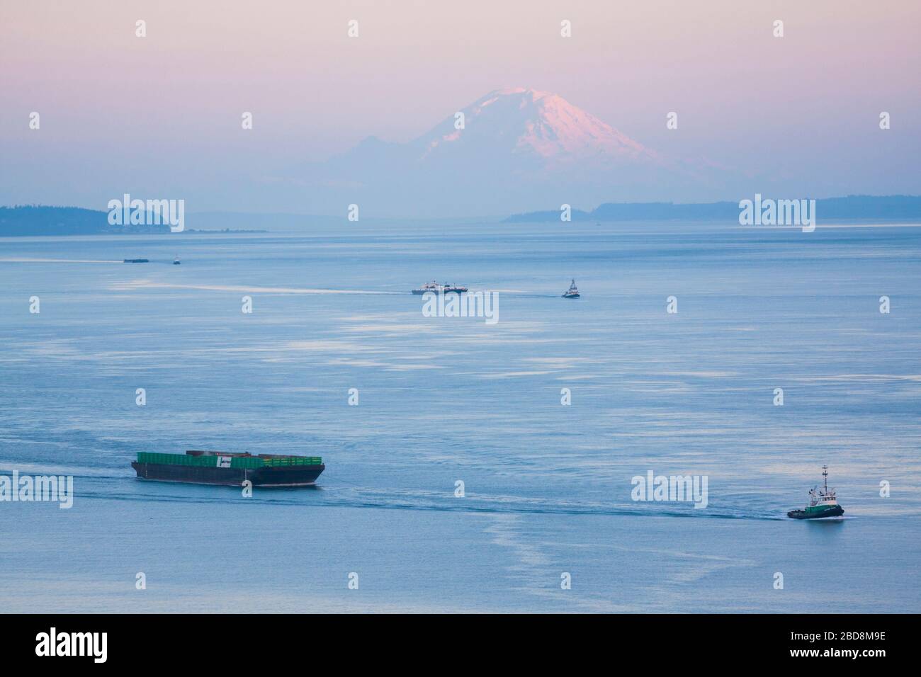 Three tugboats pull barges across Puget Sound at sunset, with Mount ...
