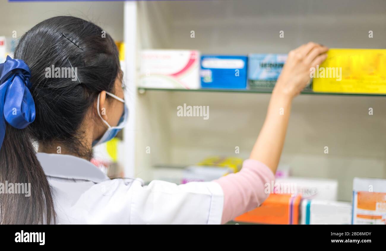 Female pharmacist taking a medicine from the shelf, wearing lab coat ...