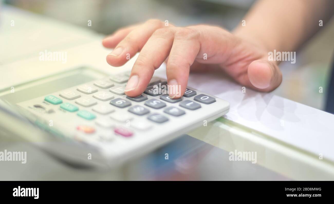 Female finger pressing the calculator to calculate and analyze income ...