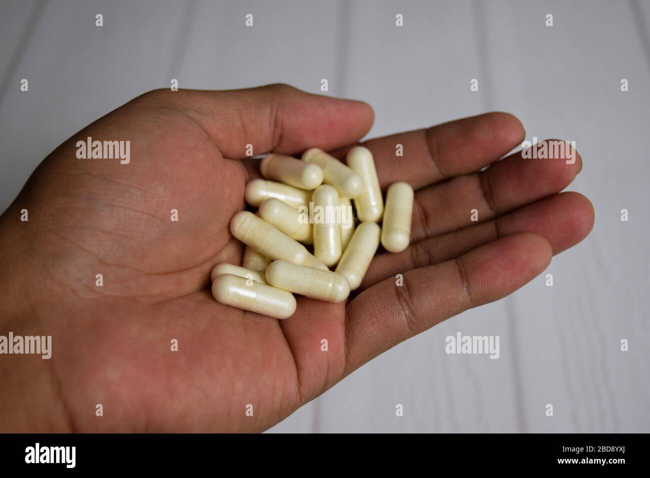 A man holding many capsules with his palm. Medical or healthcare ...