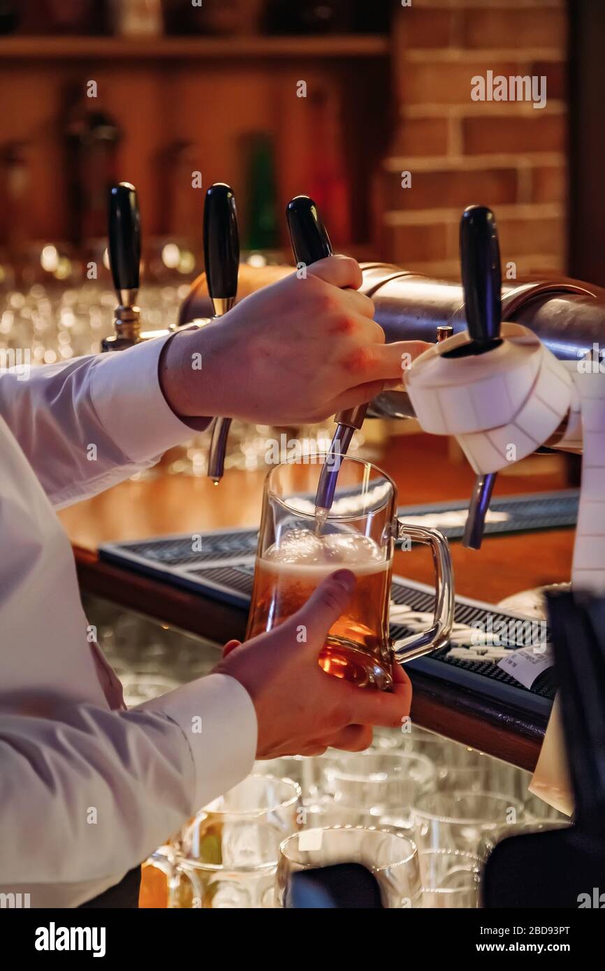 Bartender pouring draft beer from the crane into the glass in pub Stock ...