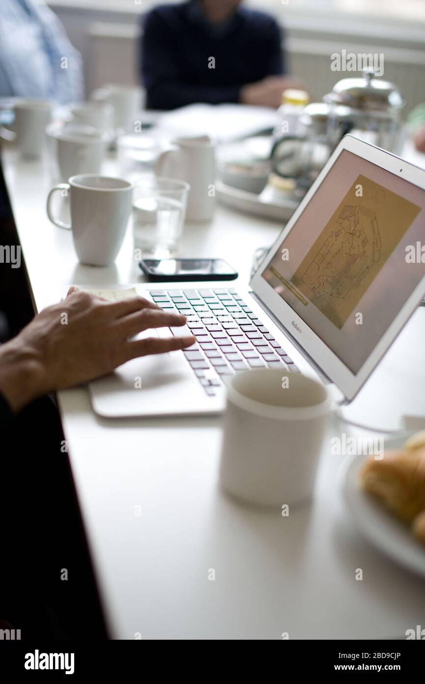 An office meeting. Table with laptop, tea and coffee Stock Photo - Alamy